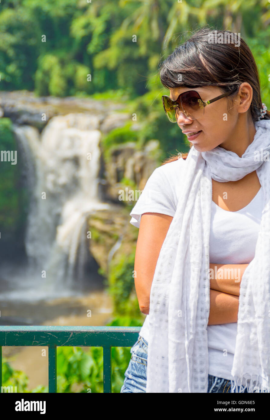 A female tourist visiting a waterfall, standing at a lookout point ...
