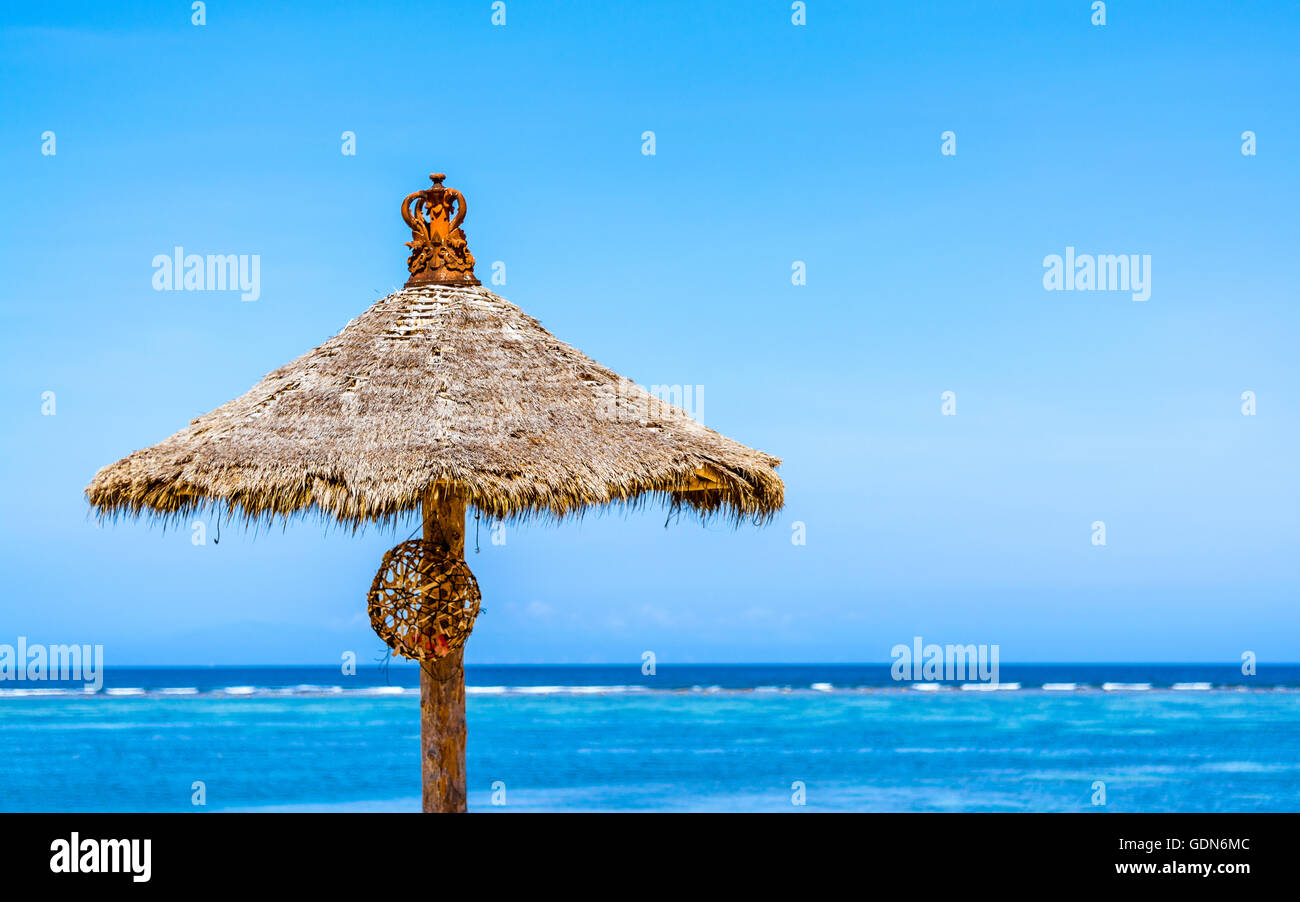 A traditionally built thatched sun shade standing on the beach on a ...