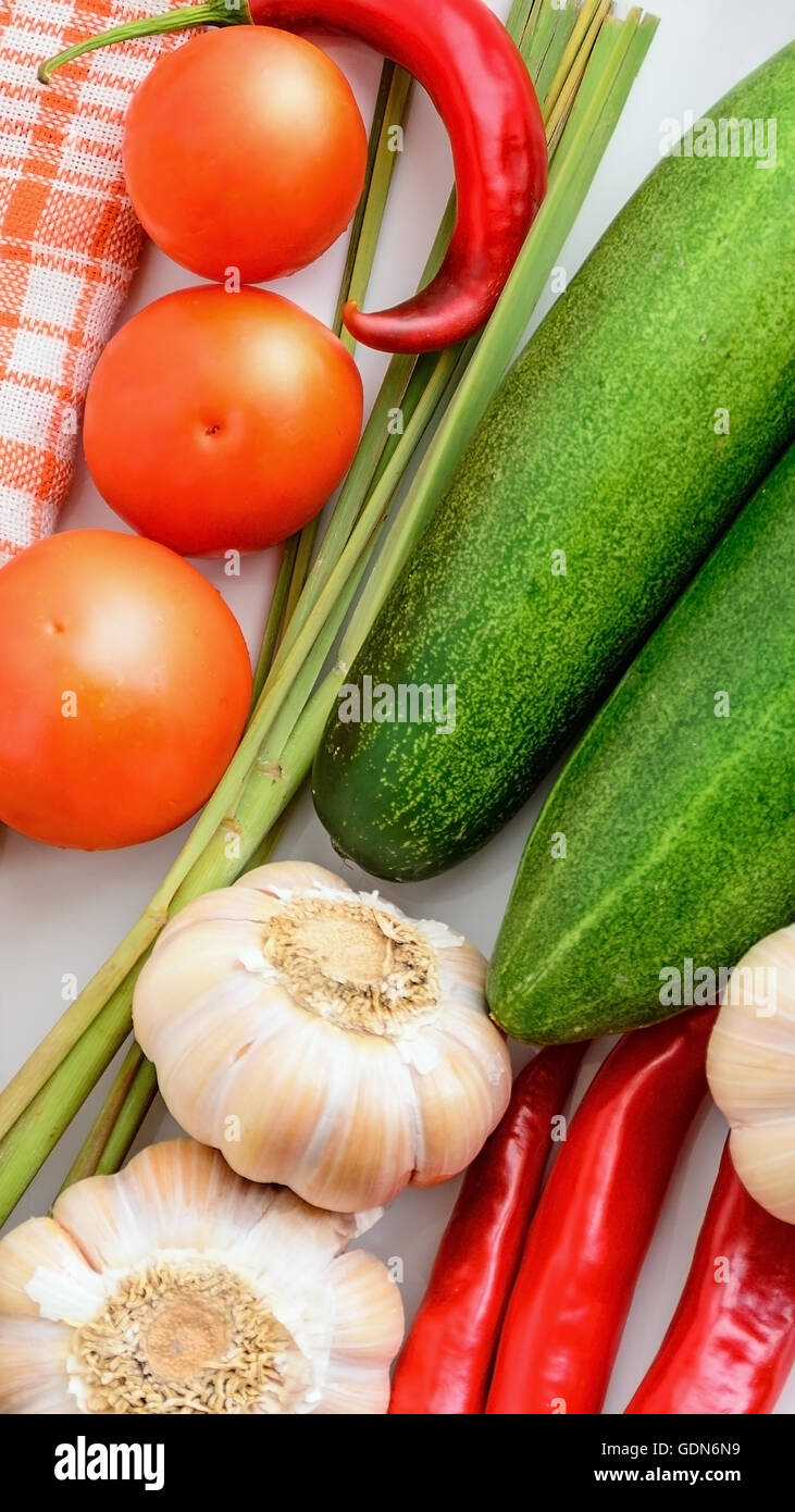 Raw vegetables layed out including cucumber, tomato, chilli, garlic ...