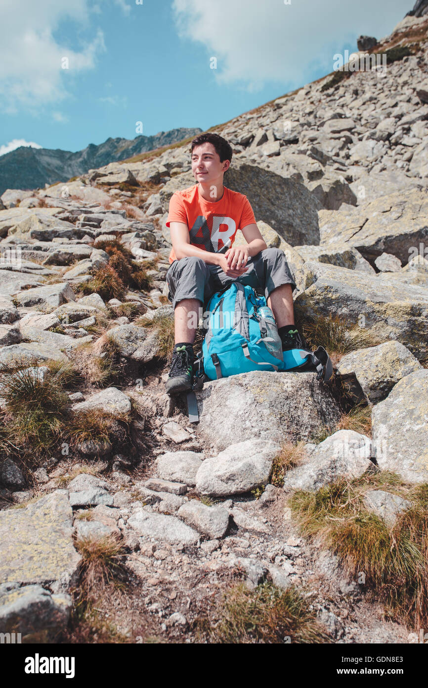 Boy resting on a rock in the mountains Stock Photo - Alamy