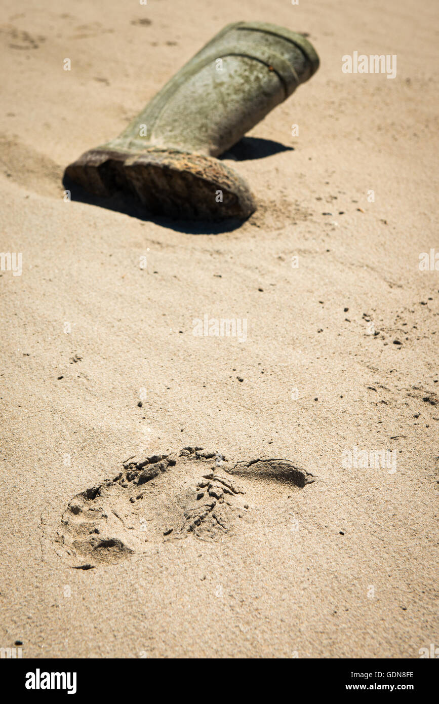 Abandoned wellington boot and footprint on beach Stock Photo - Alamy