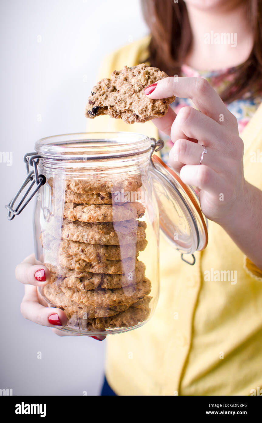 Woman holding cookie jar with cookies in one hand Stock Photo - Alamy