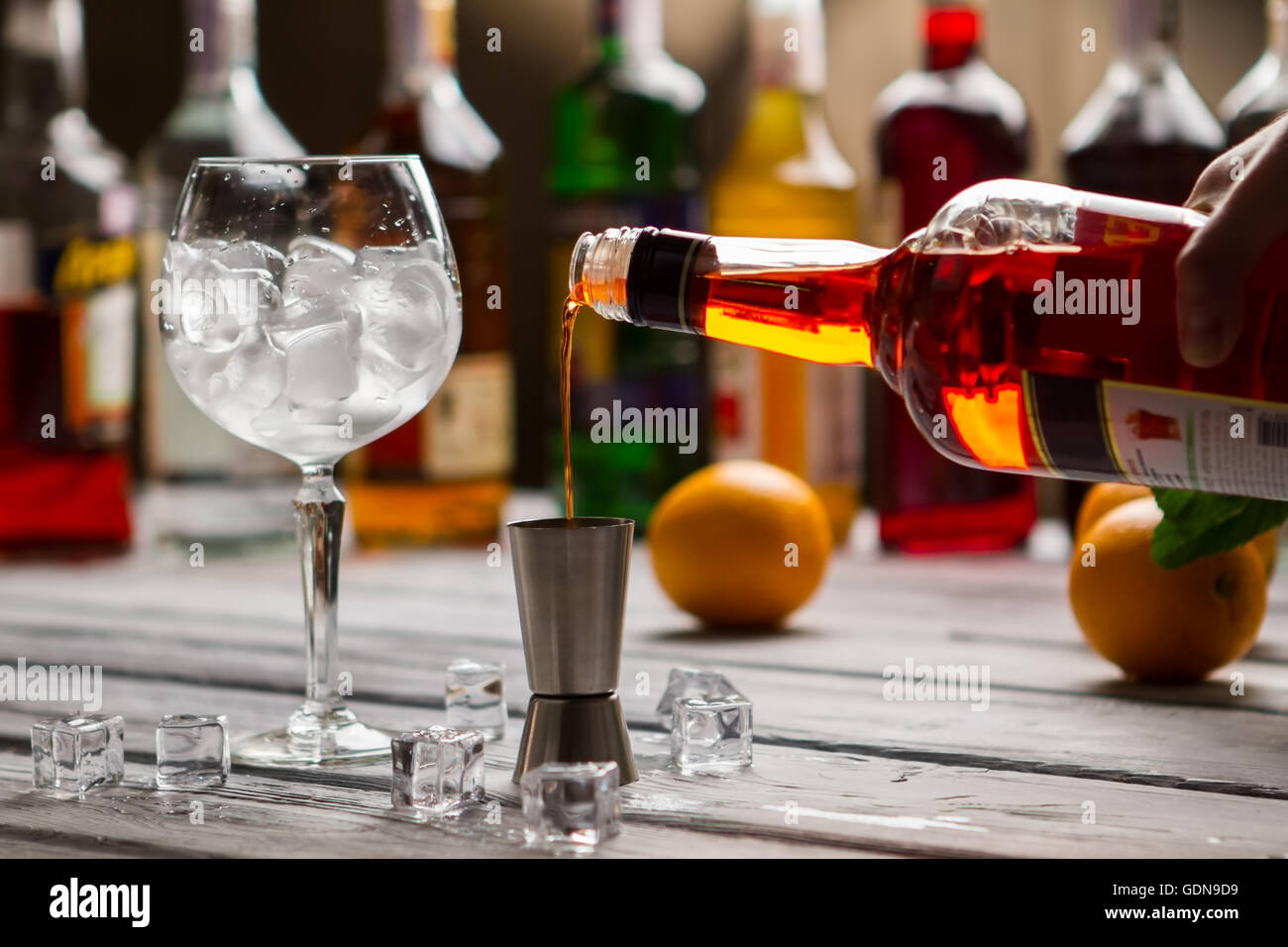 Bottle pours liquid into jigger Stock Photo - Alamy