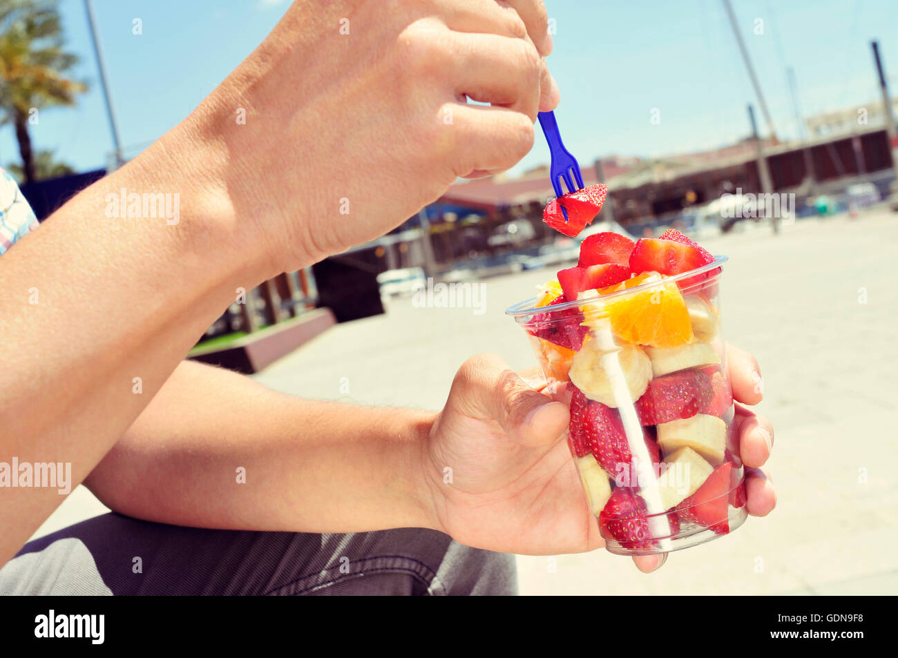 closeup of a young caucasian man eating a fruit salad in a clear ...