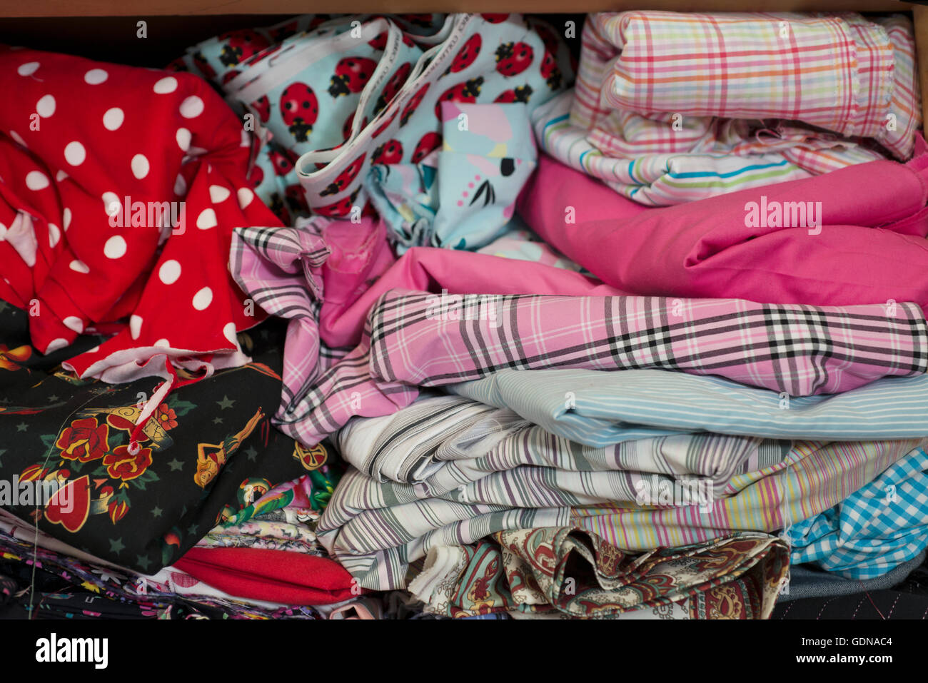 A pile of textile or cloth of various colours and designs in wooden ...