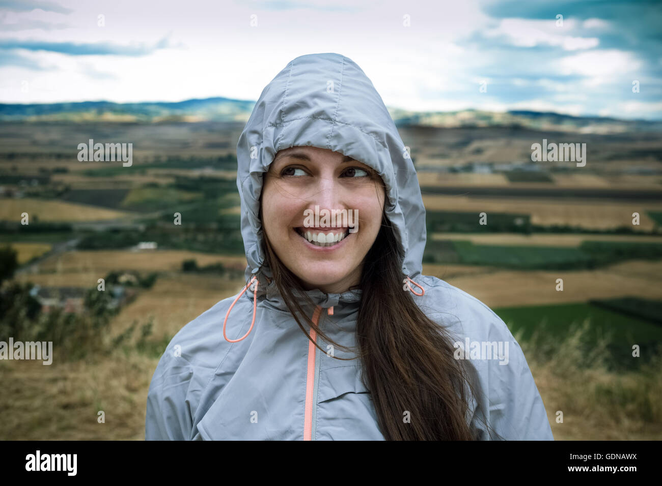 Young woman smiling after a long hike in windy weather, looking away ...