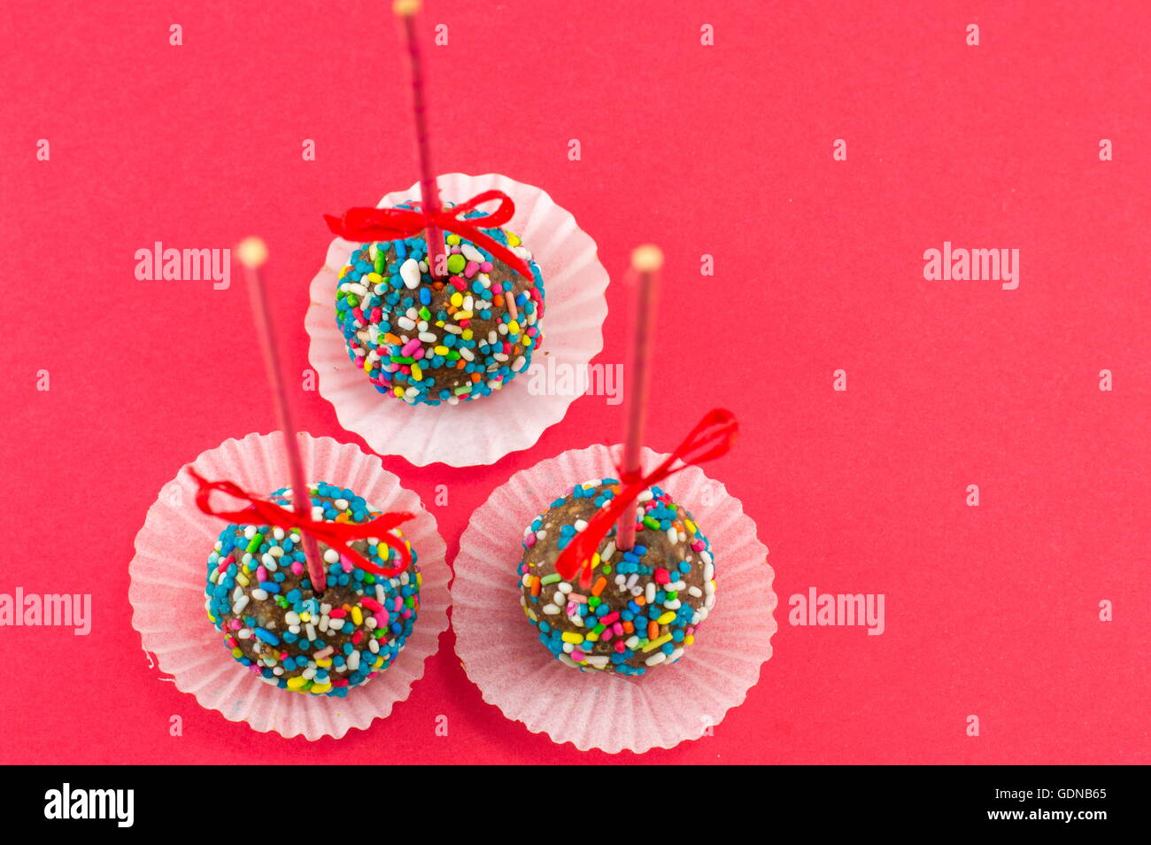 Three cake pops on a red background Stock Photo - Alamy