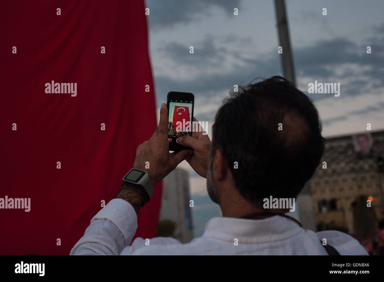 A Turkish man using a mobile phone to photograph a Turkish flag at a ...