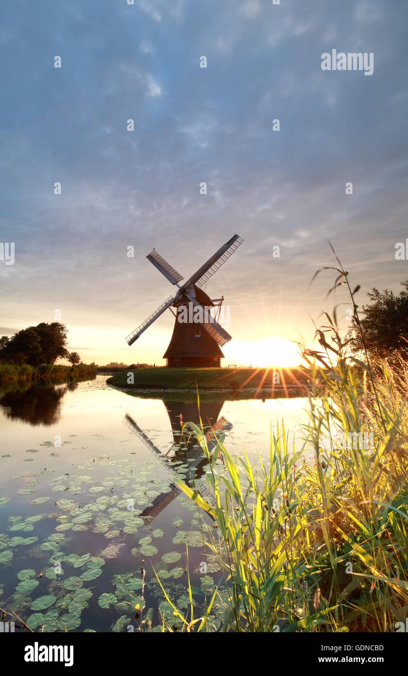 gold sunshine behind Dutch windmill by river, Holland Stock Photo - Alamy