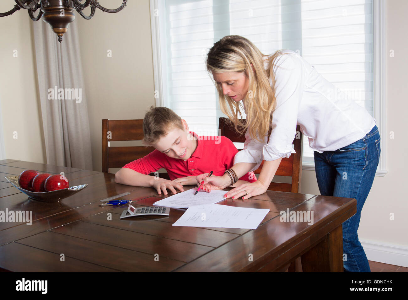 mother at a table home helping her small son with his homework Stock ...