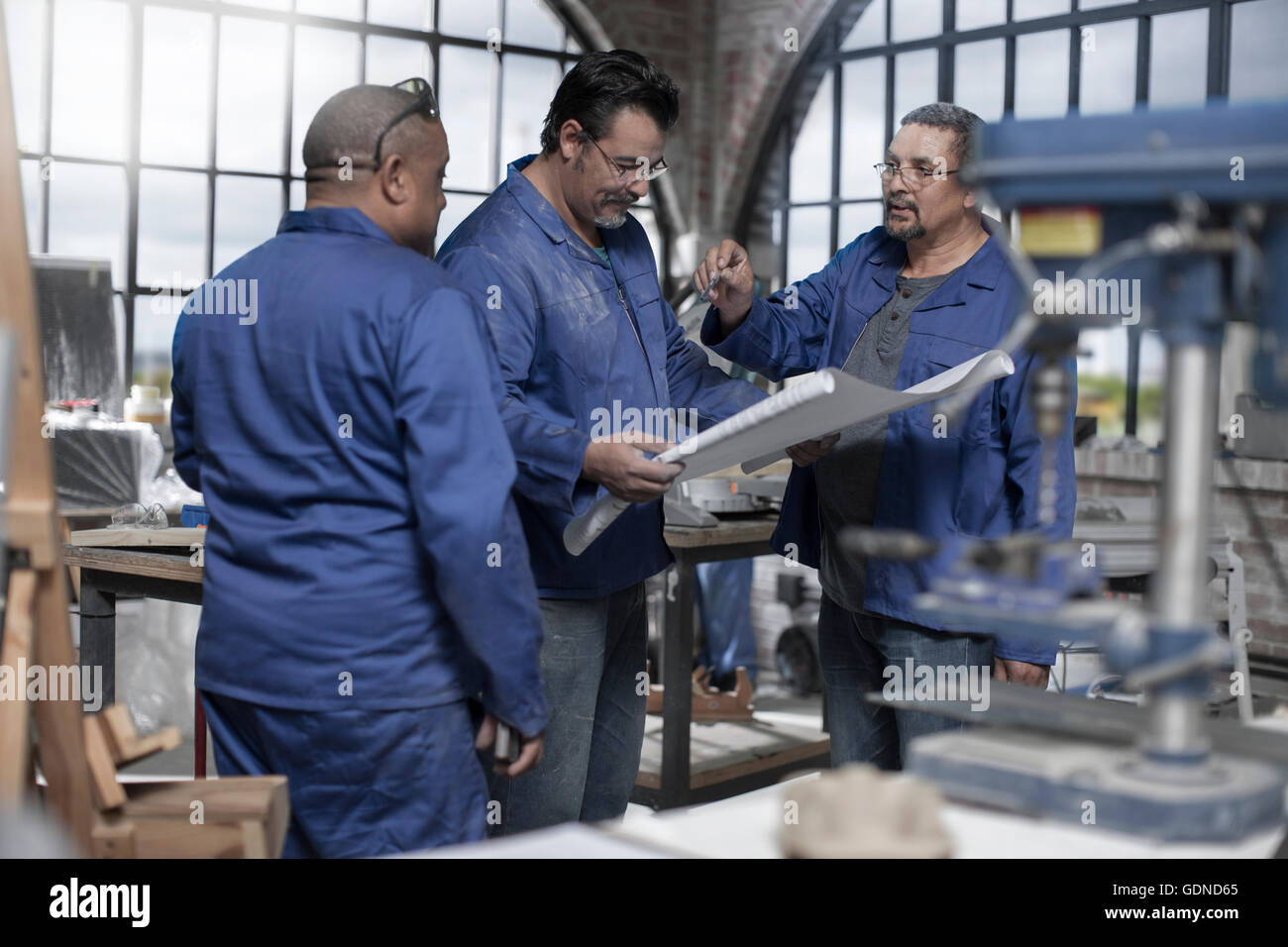 Team discussing blueprint in workshop Stock Photo - Alamy