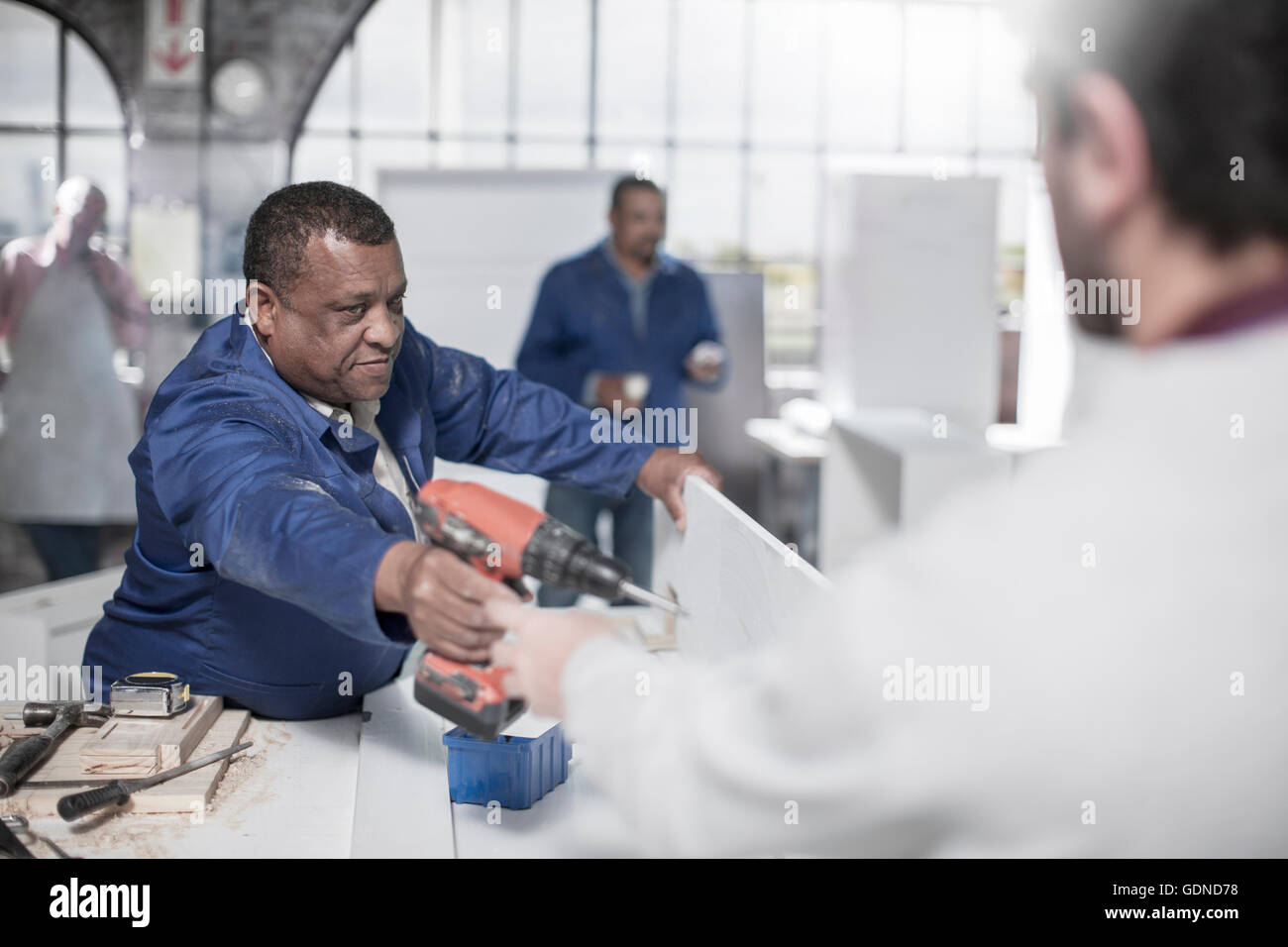 Carpenters handing over hand drill in wood workshop Stock Photo - Alamy
