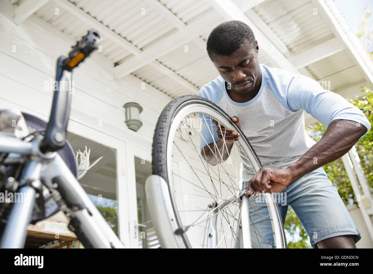 Man fixing bicycle in porch Stock Photo - Alamy