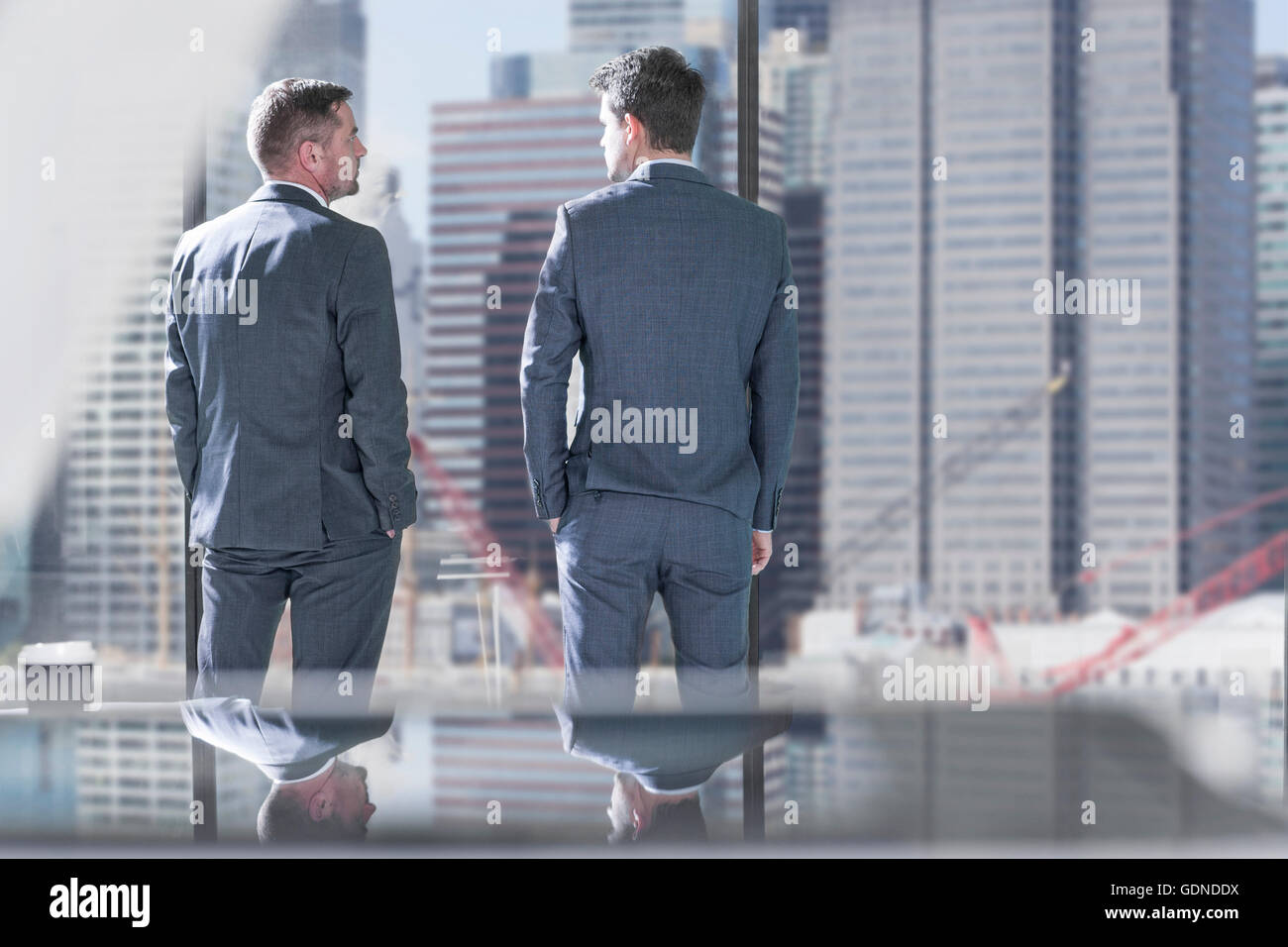 Businessmen in discussion in front of office window Stock Photo - Alamy