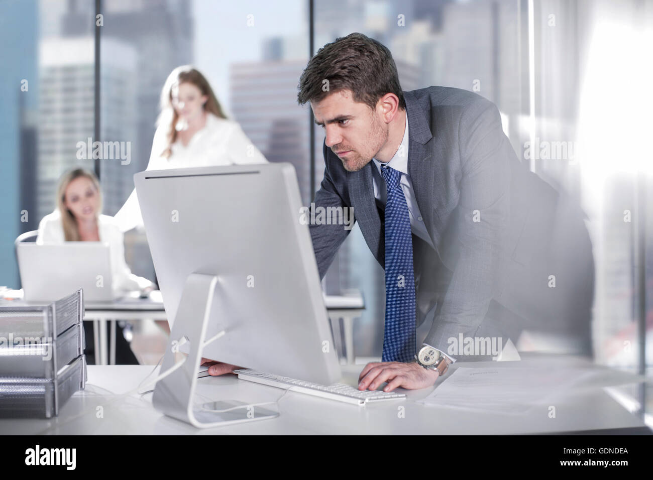 Businessman using computer in office, colleagues working in background ...