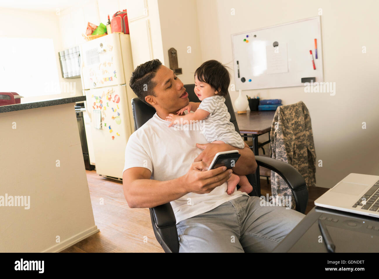 Father using mobile phone and carrying baby in arms Stock Photo - Alamy