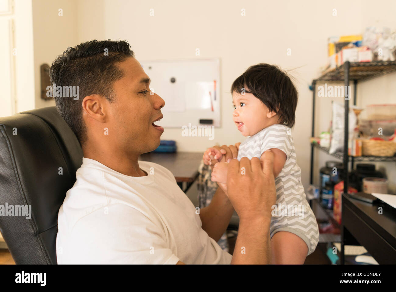Father playing with baby at work desk Stock Photo - Alamy