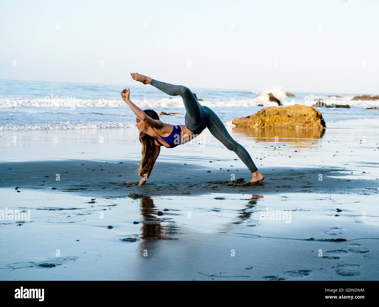Young female dancer balancing on hand at beach, Los Angeles, California ...