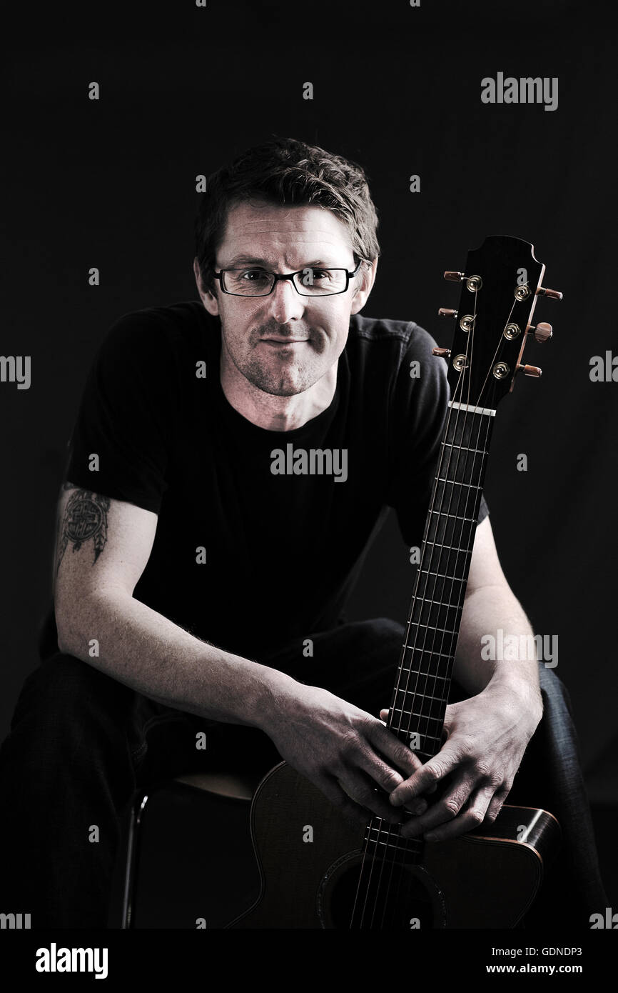 Low key portrait of mid adult man and his acoustic guitar Stock Photo ...