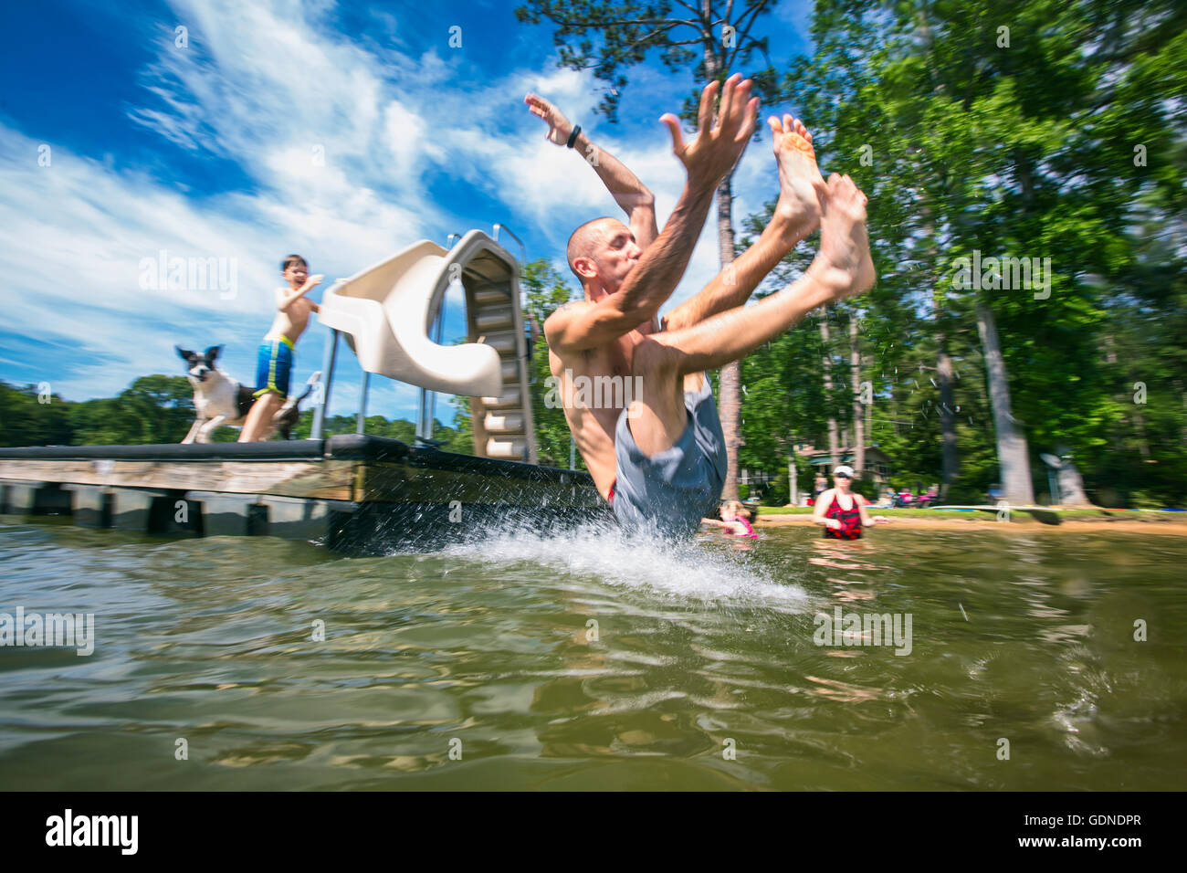 Man splashing into lake from pier slide at Jackson Lake, Georgia, USA ...