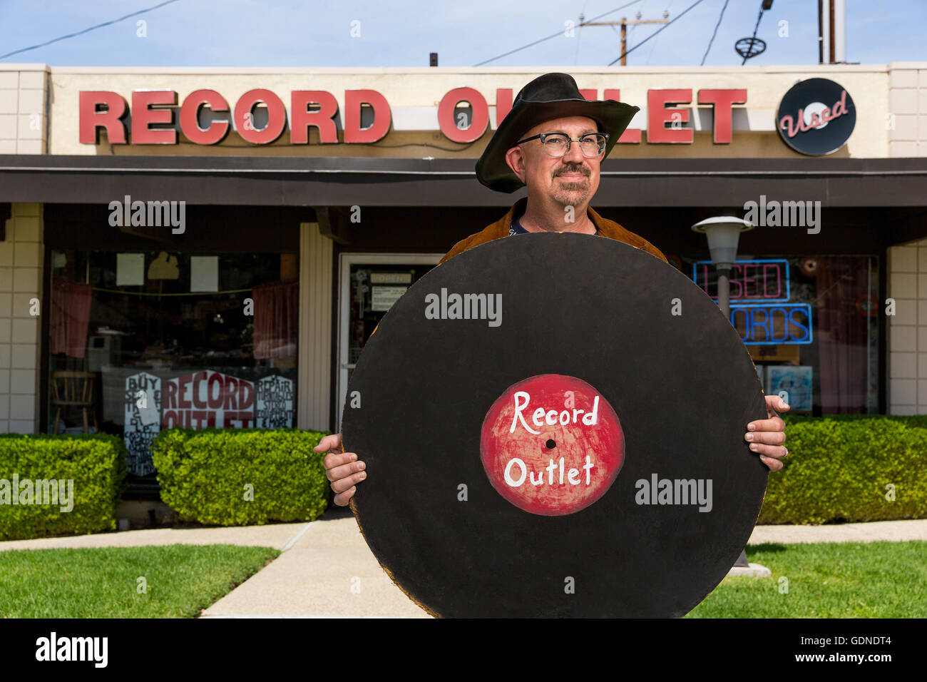 Portrait of mature man outside record shop, holding large imitation ...