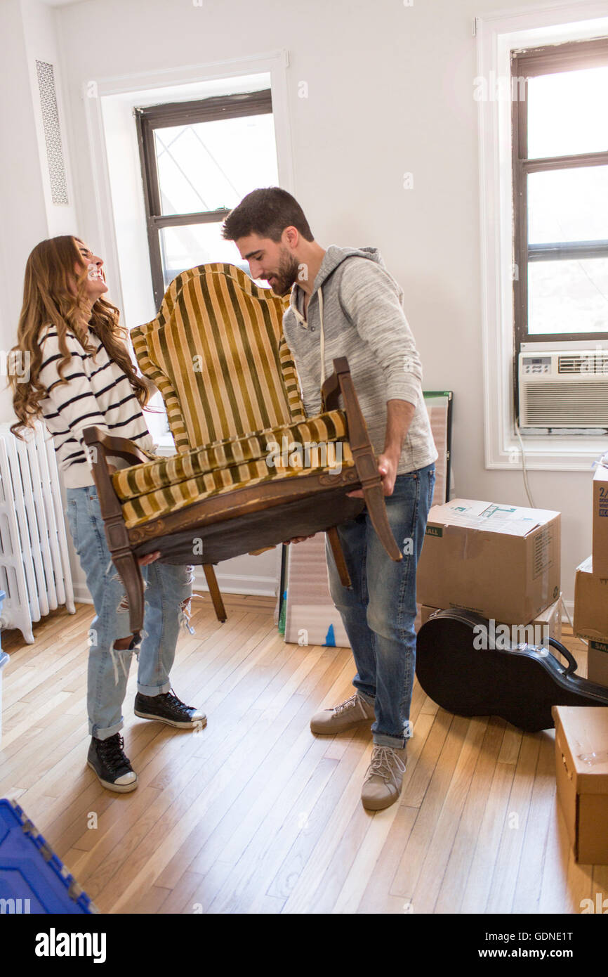 Moving house: Young couple lifting chair Stock Photo - Alamy
