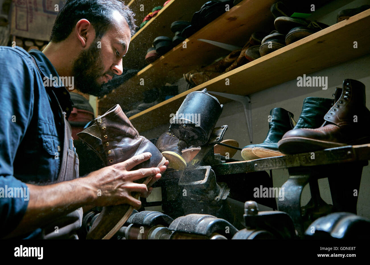 Male cobbler in traditional shoe workshop repairing boot heel Stock ...