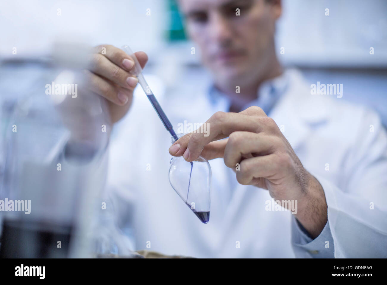 Mid adult man injecting liquid into test tube Stock Photo - Alamy