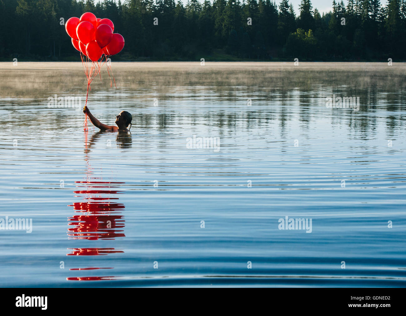 Woman in water holding bunch of red balloons Stock Photo - Alamy