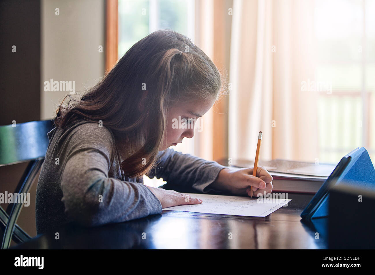 Side view of girl at desk writing Stock Photo - Alamy