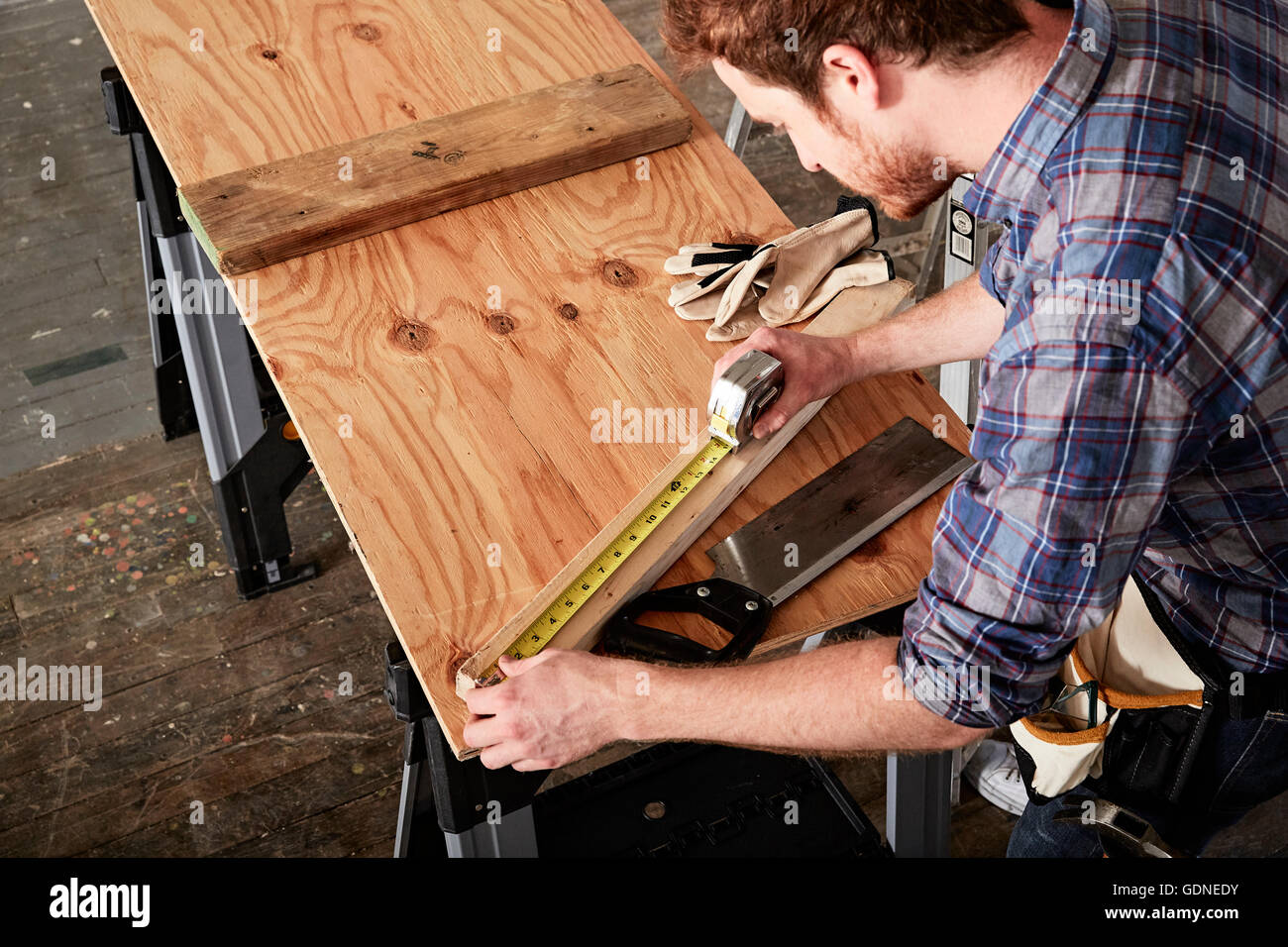 Over shoulder view of carpenter in workshop measuring timber Stock ...