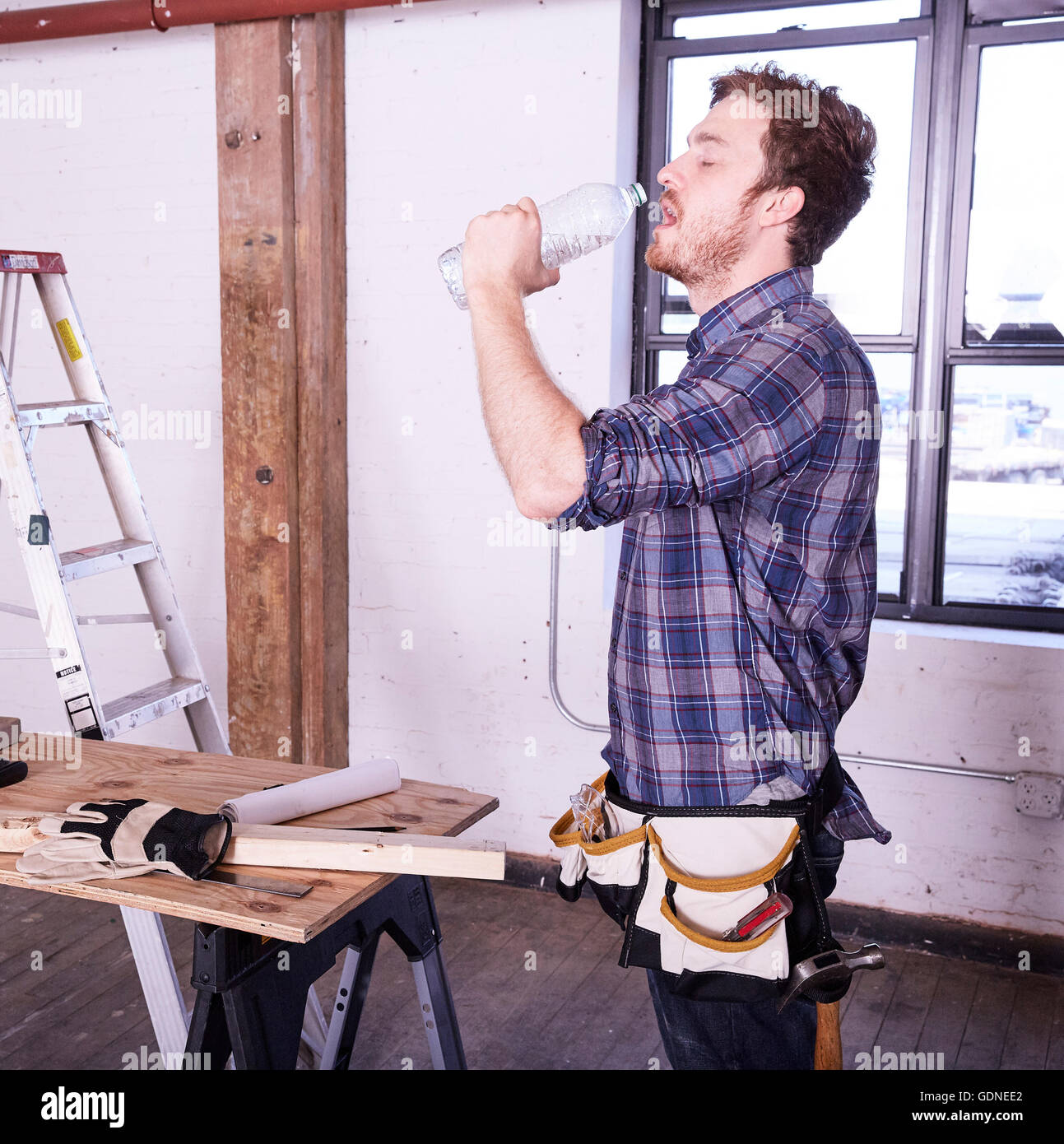 Carpenter in workshop drinking from water bottle Stock Photo - Alamy