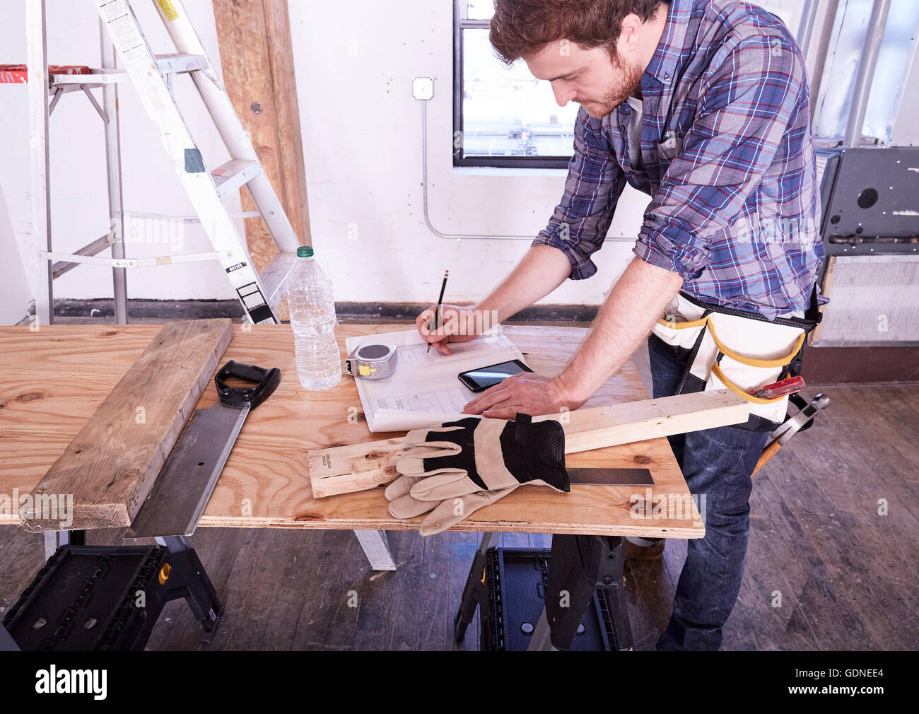 Carpenter in workshop writing in notebook Stock Photo - Alamy
