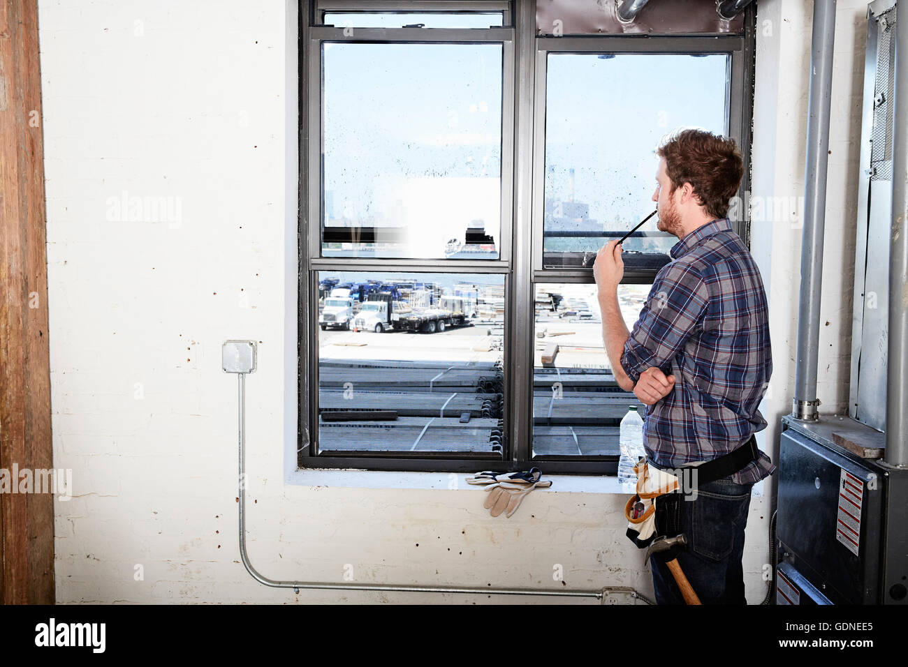 Carpenter looking out of window thinking Stock Photo - Alamy