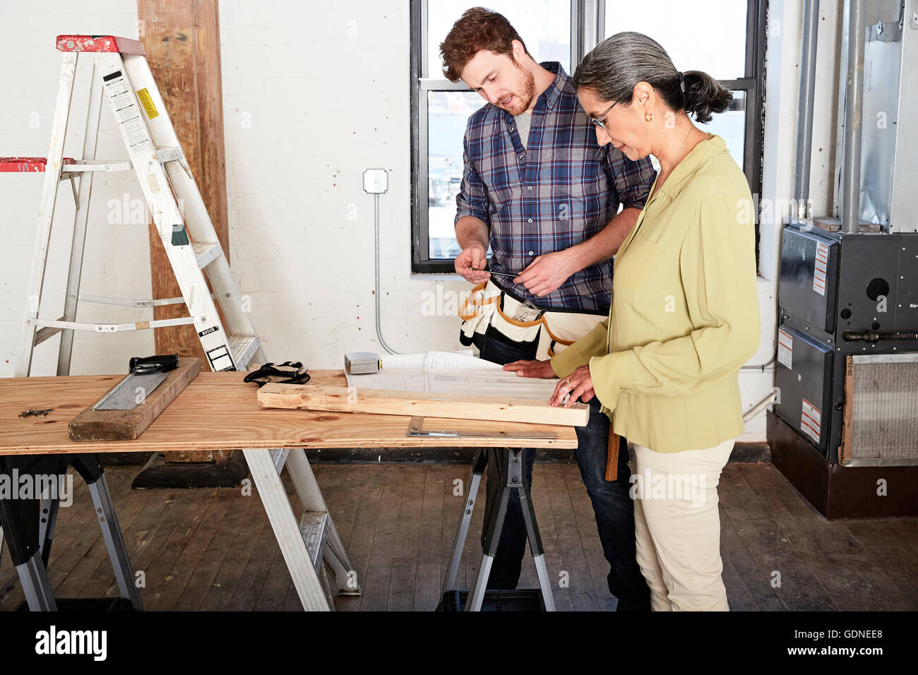 Carpenter looking at blueprint with client Stock Photo - Alamy