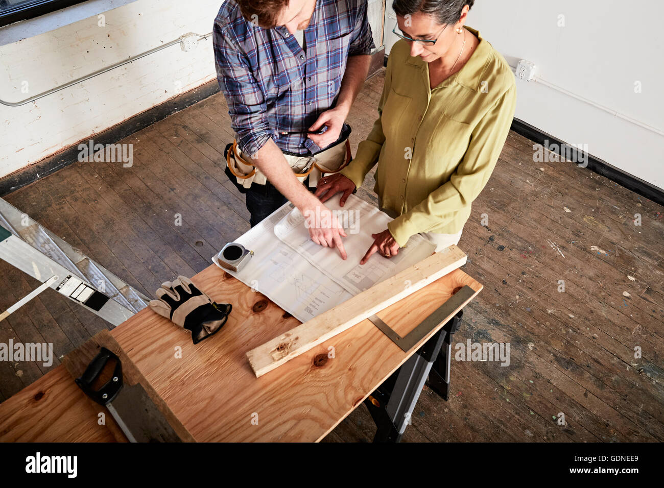 Carpenter looking at blueprint with client Stock Photo - Alamy