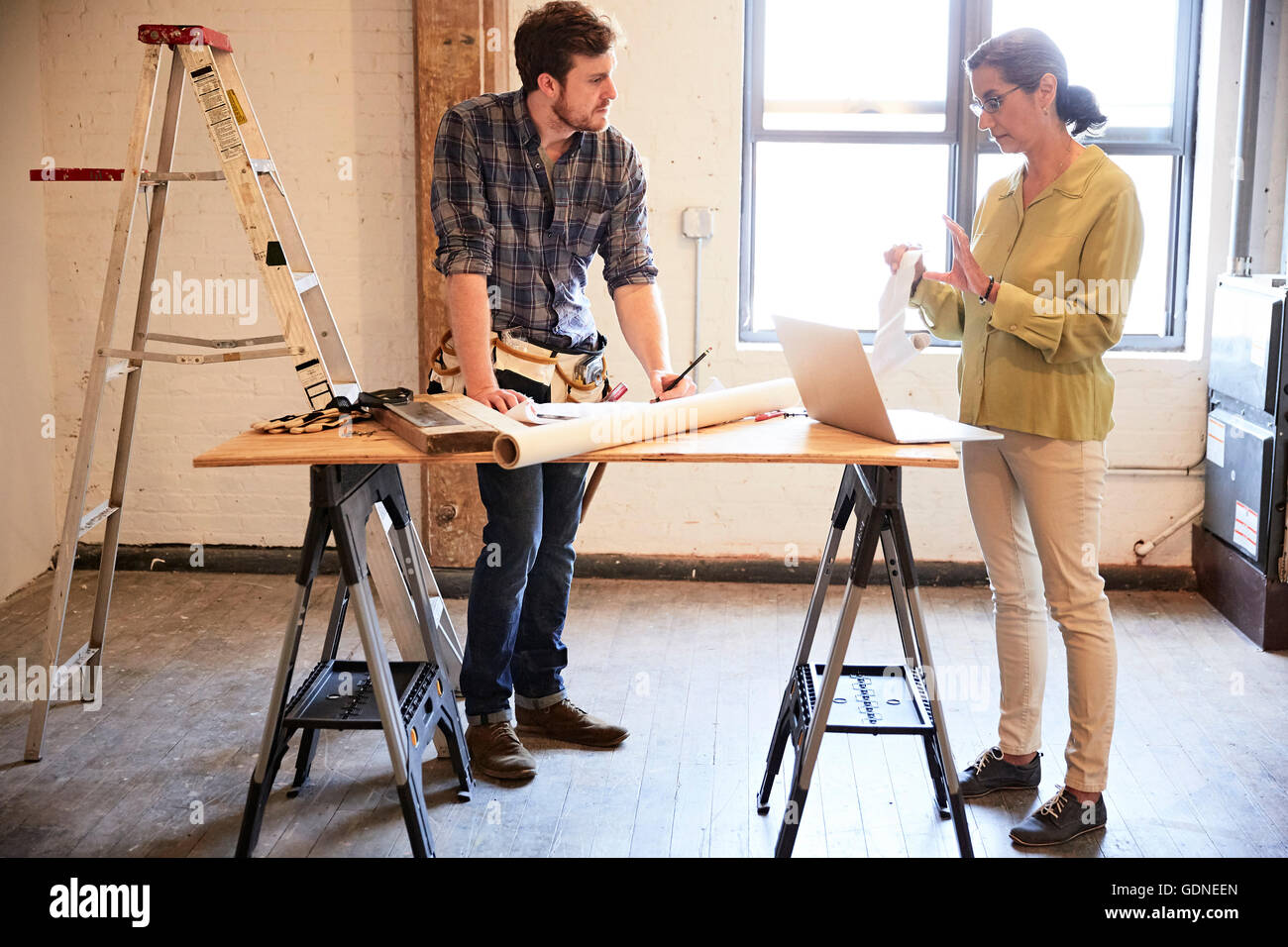 Carpenter and client at workbench discussing blueprint Stock Photo - Alamy