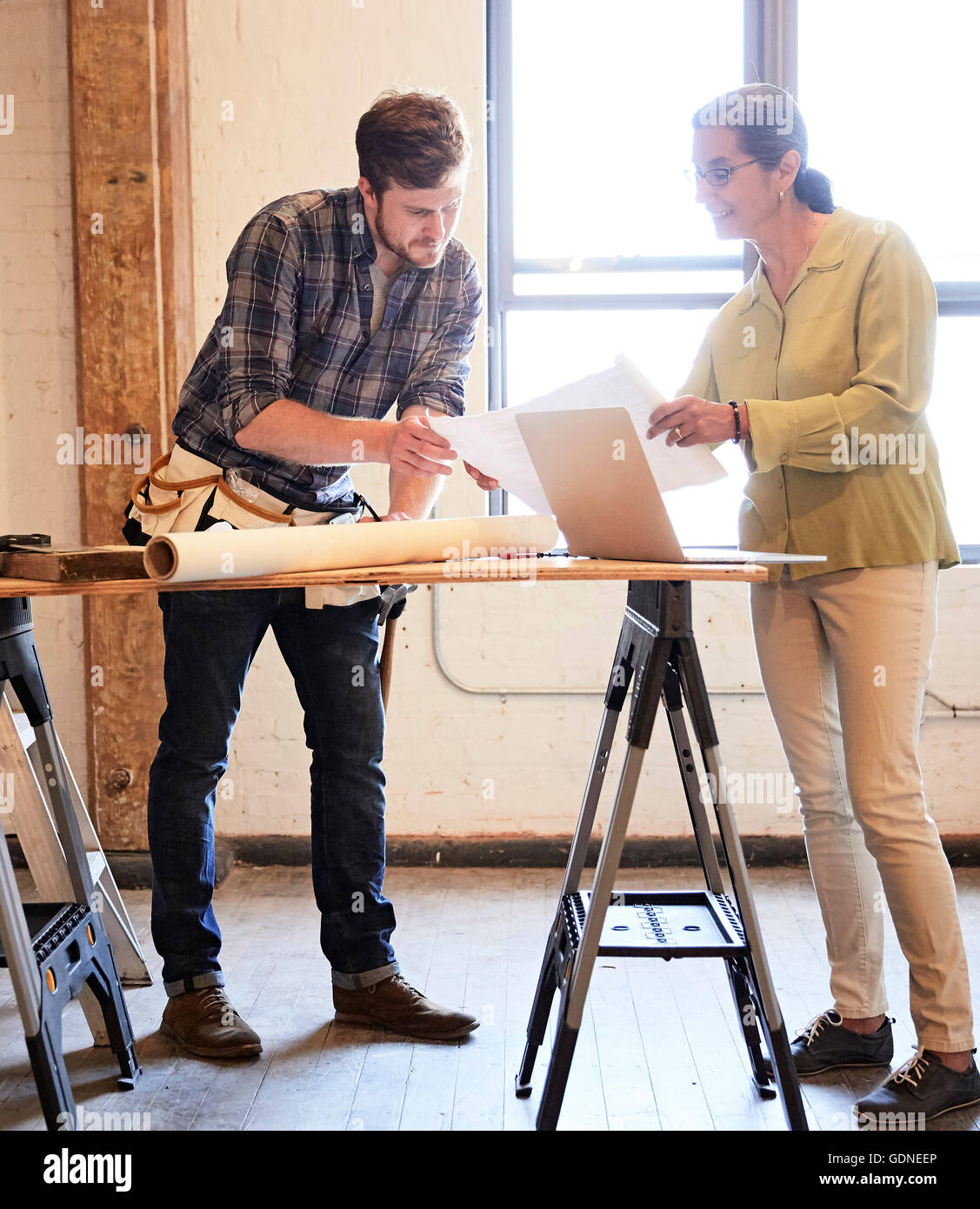 Carpenter and client at workbench discussing blueprint Stock Photo - Alamy