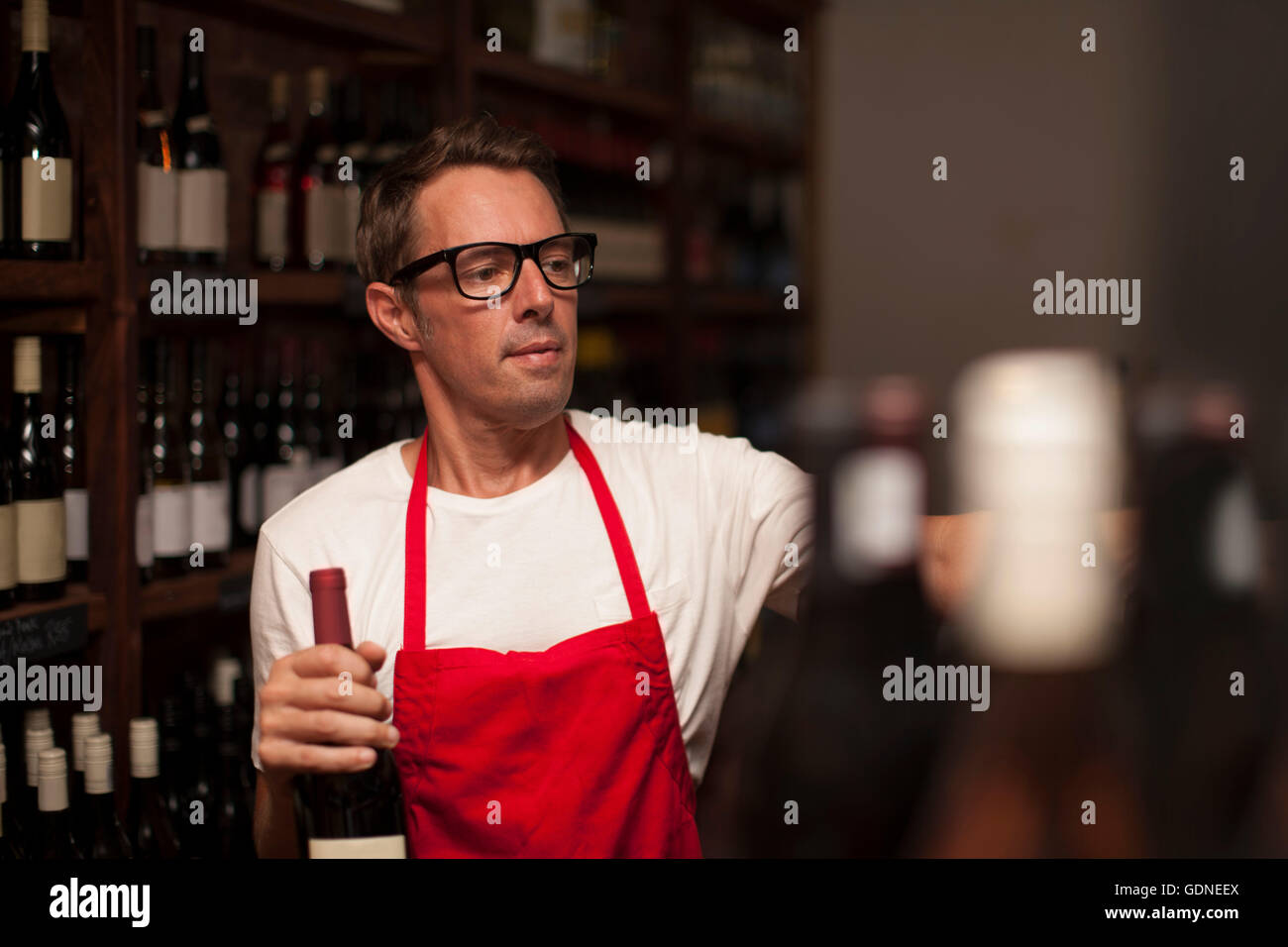 Man working in wine shop holding bottles of wine Stock Photo - Alamy