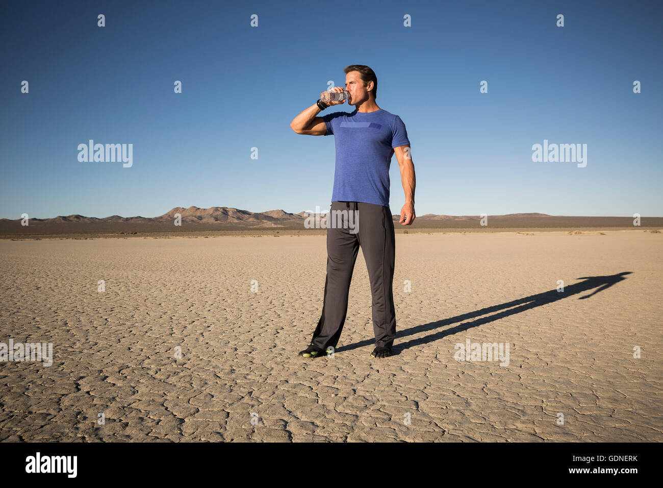 Man training, drinking bottled water on dry lake bed, El Mirage ...