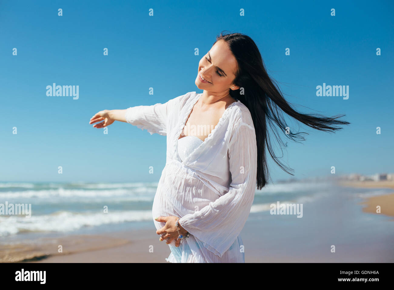 Expectant mother in white dress on a background of blue sky Stock Photo ...
