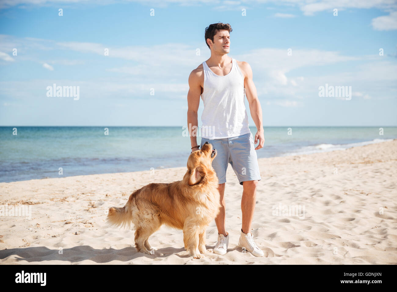 Closeup of serious handsome young man with his dog on the beach Stock ...