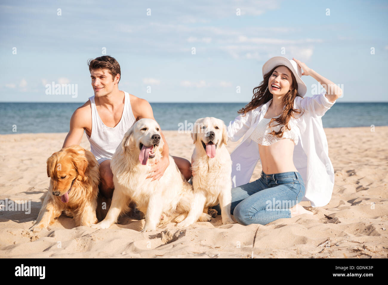 Happy young couple with three dogs sitting on the beach Stock Photo - Alamy