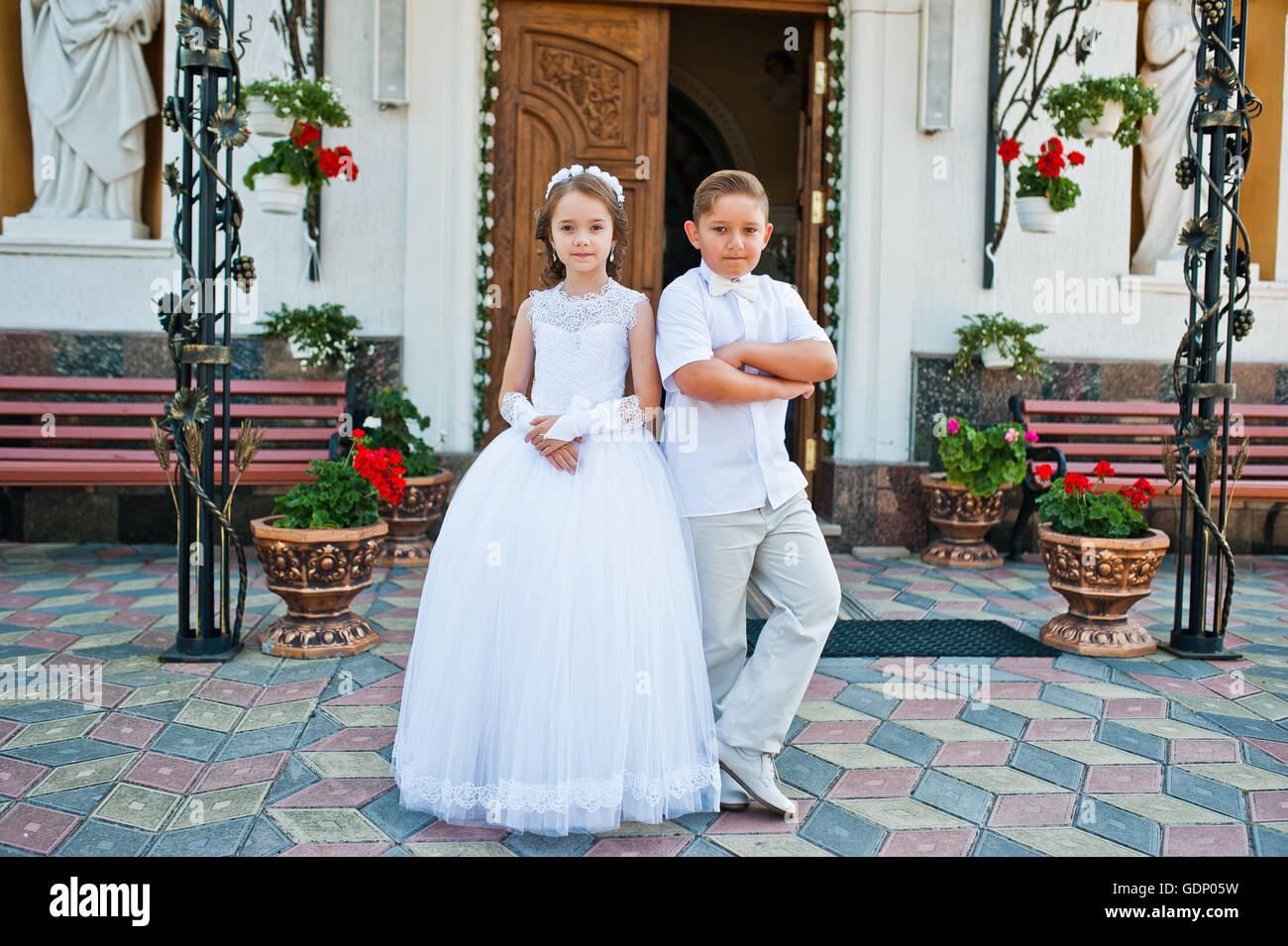 First holy communion, brother and sister stay at white dress background ...