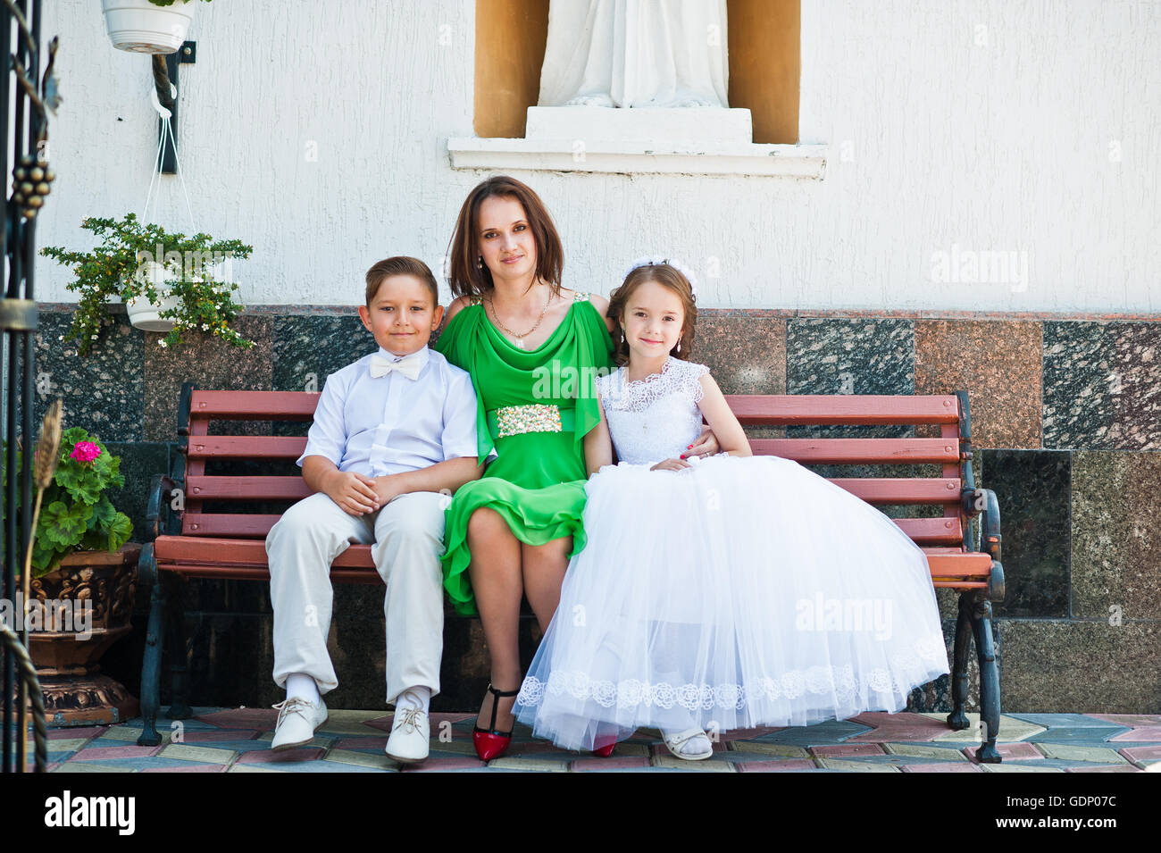 Happy family at first holy communion sitting on bench background church ...