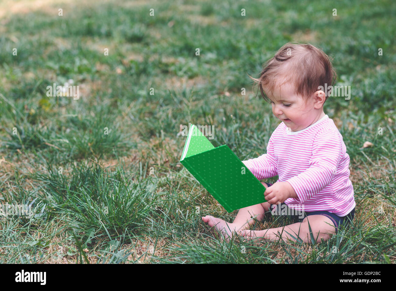 Little baby girl watching a book with pictures Stock Photo - Alamy
