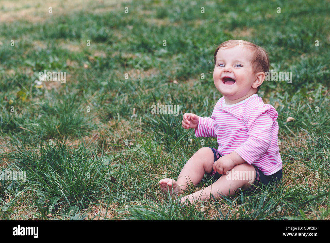 Smiling baby girl sitting on a grass in the garden Stock Photo - Alamy