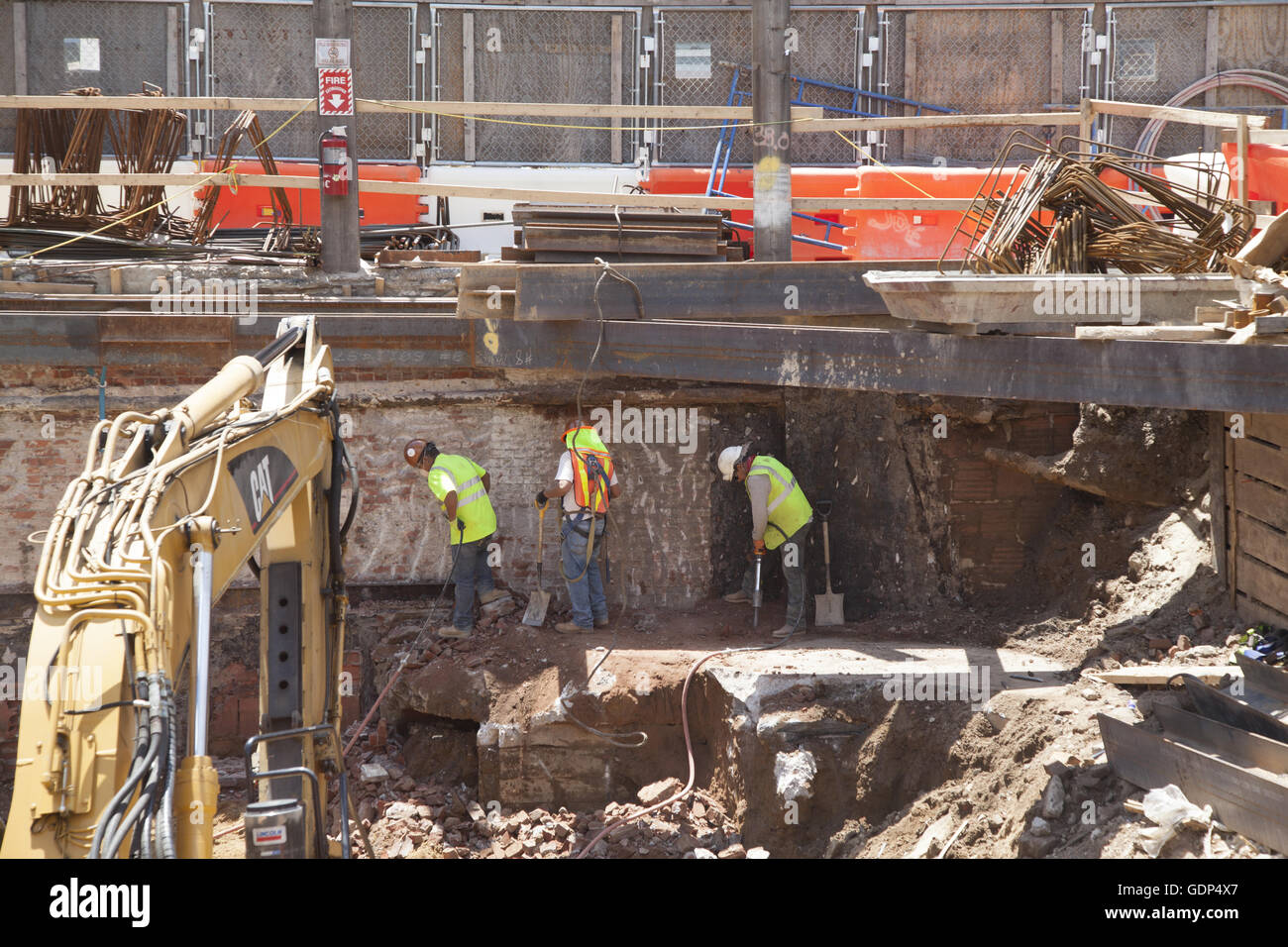 Construction workers work on the foundation for another tall building ...