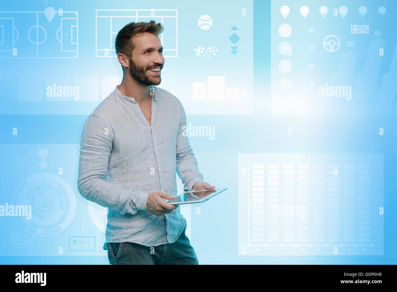 Man using digital tablet, graphical screen with gaming images behind ...