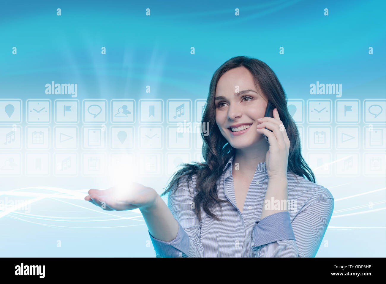 Young woman using mobile phone, digital icons behind her, light beam ...